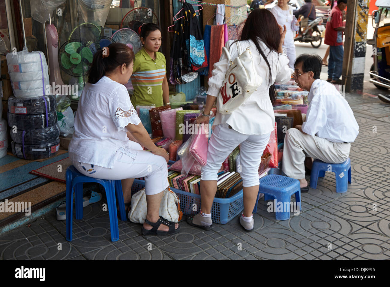 A girl selliing at a street market stall with customers in Korat ...