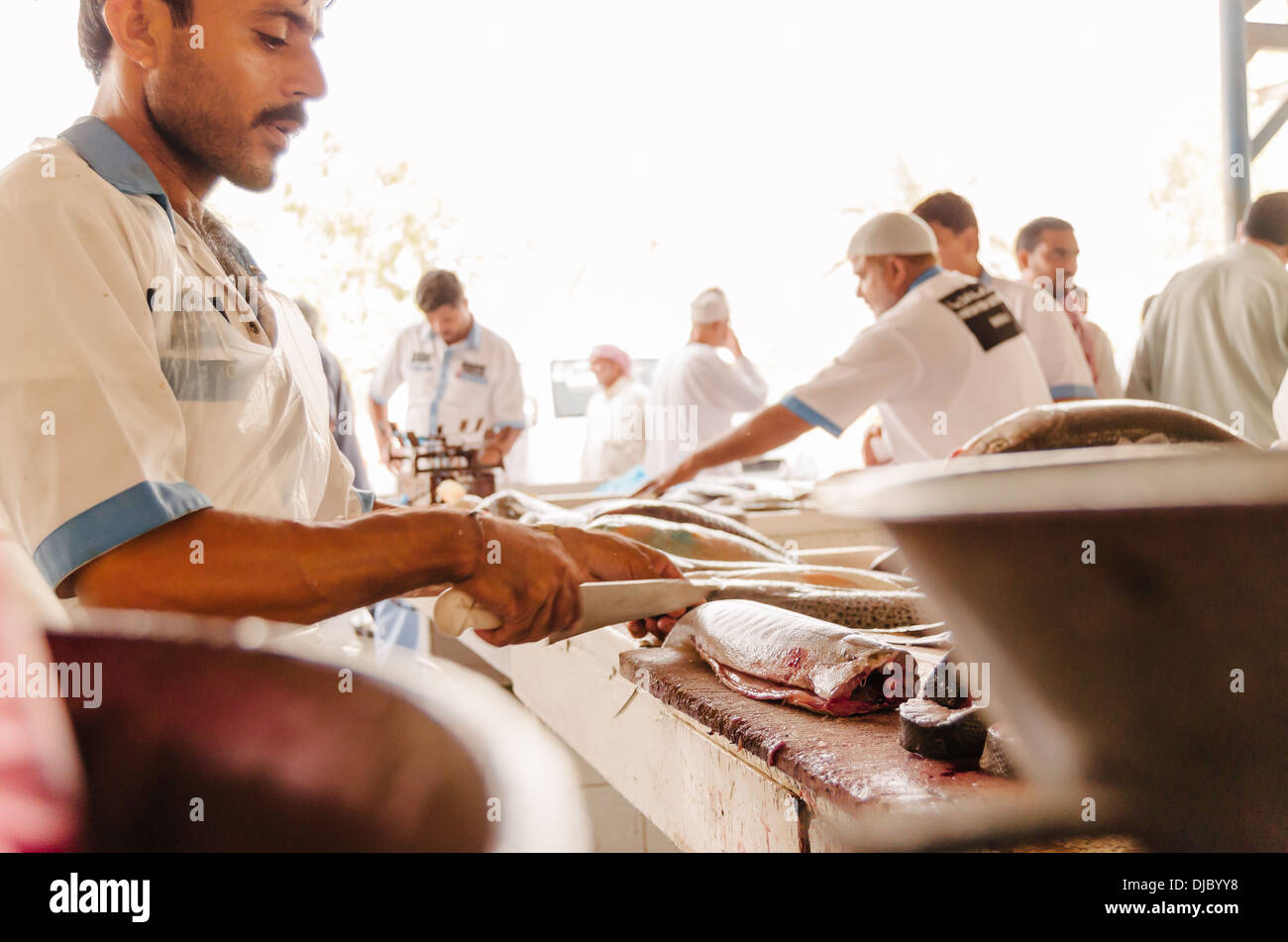 Skilled butcher chopping fish with a sharp knife on top of a bloody ...