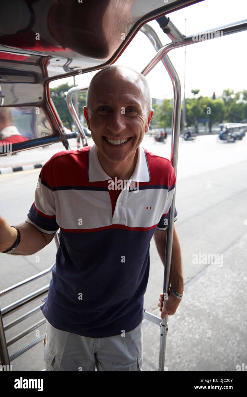 Happy European tourist man rides on the local small pay as you go bus ...