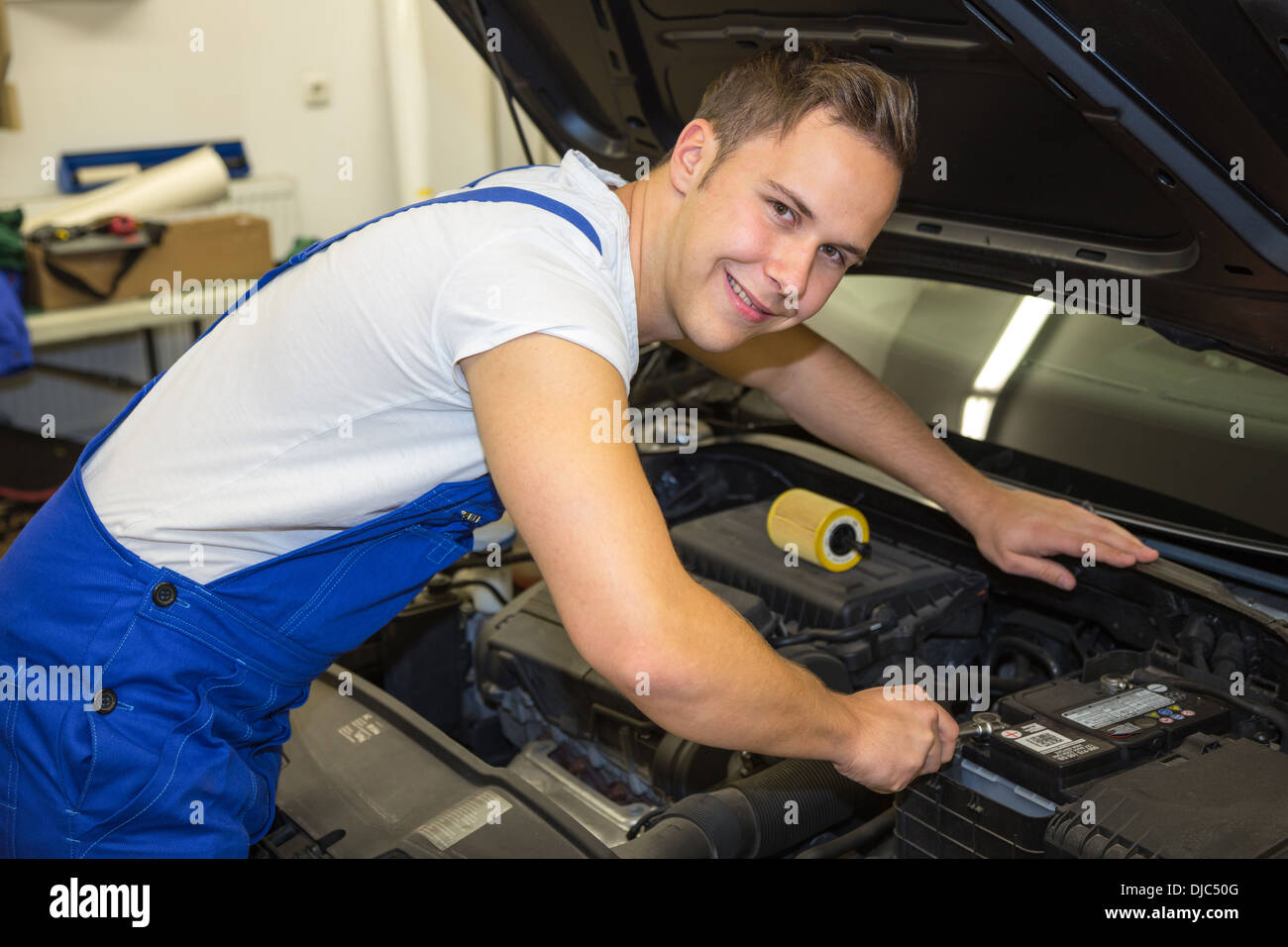Mechanic with tools in garage or workshop repairing the motor of a car ...