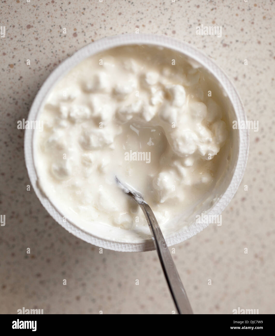 Close-up of white cottage cheese in plastic container and teaspoon on ...