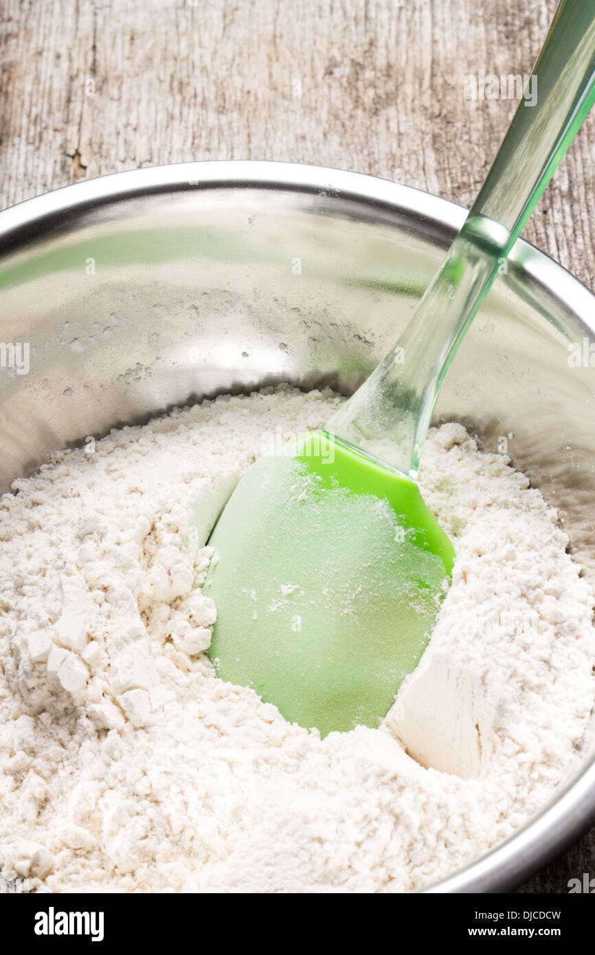 Mixing wheat flour in metallic bowl on wooden board Stock Photo - Alamy