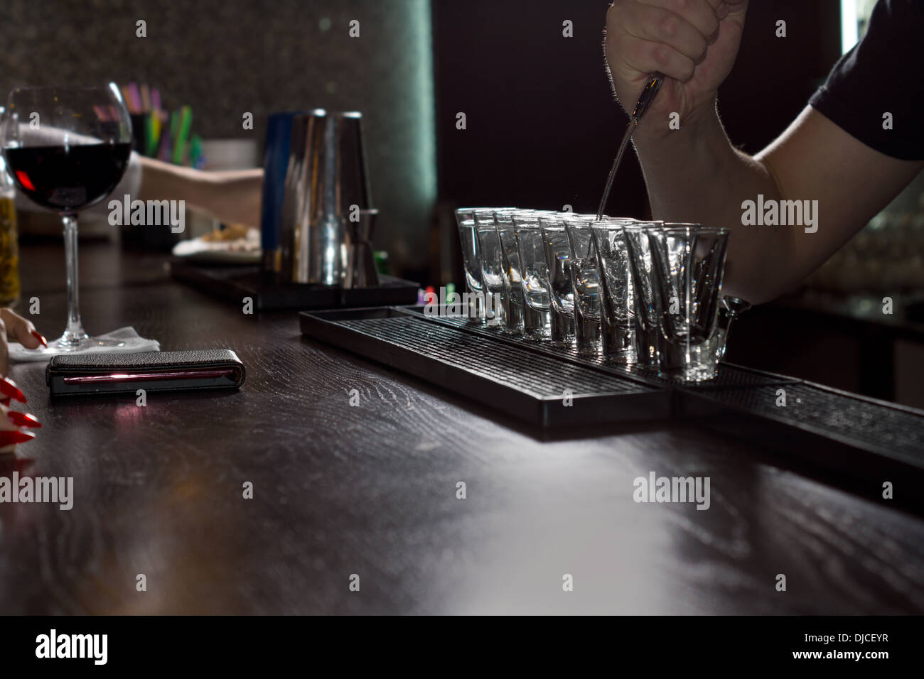 Row of glasses on a bar counter with the arm of a barman using a ...