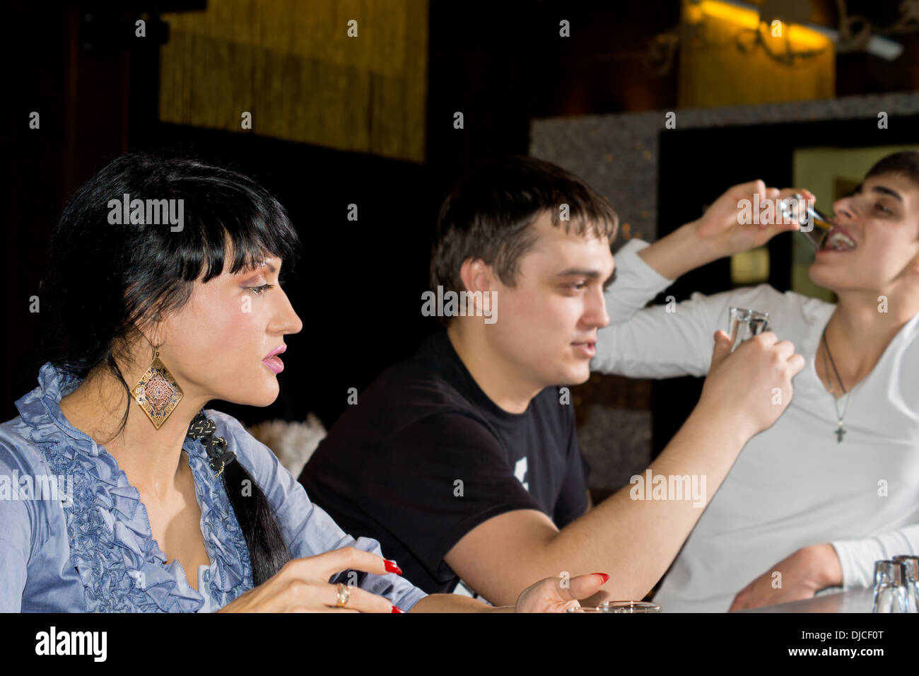 Three friends drinking shots of vodka followed by salt chasers as they ...