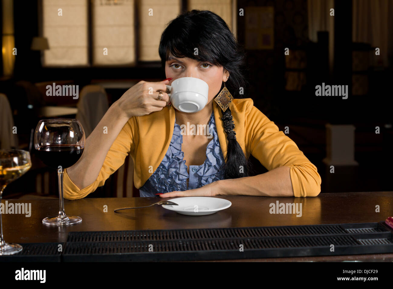 Woman enjoying a cup of coffee in a bar drinking from the cup and ...