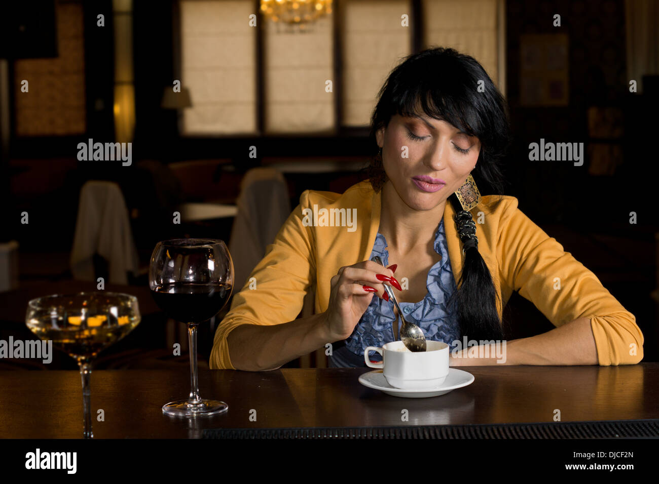 Elegant woman sitting alone drinking coffee at the bar counter in a ...
