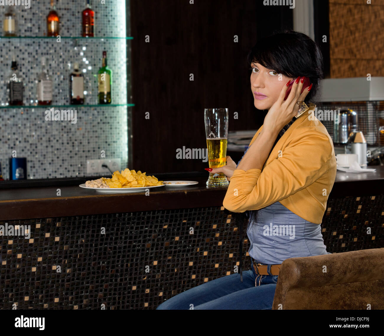 Young woman sitting at a bar counter in a nightclub listening to a ...