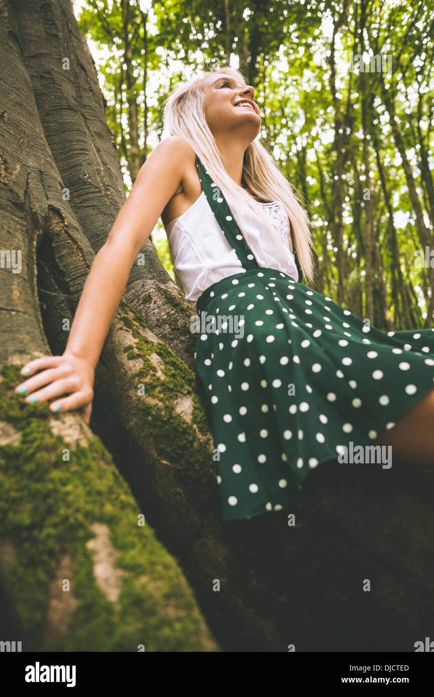 Low angle picture of smiling gorgeous blonde leaning against tree Stock ...