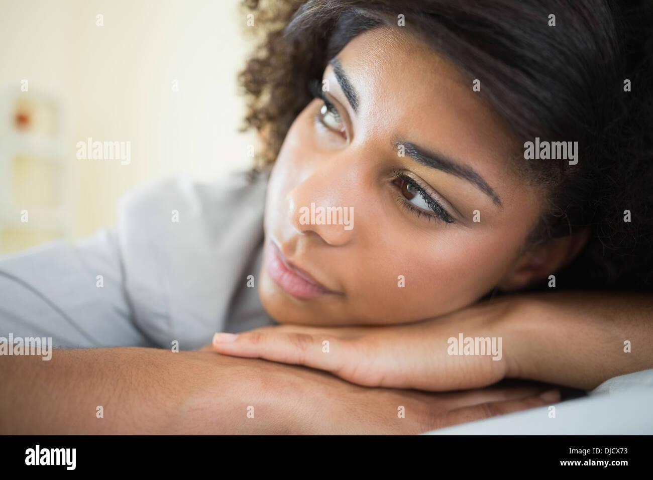 Pretty pensive brunette resting head on hand lying on bed Stock Photo ...