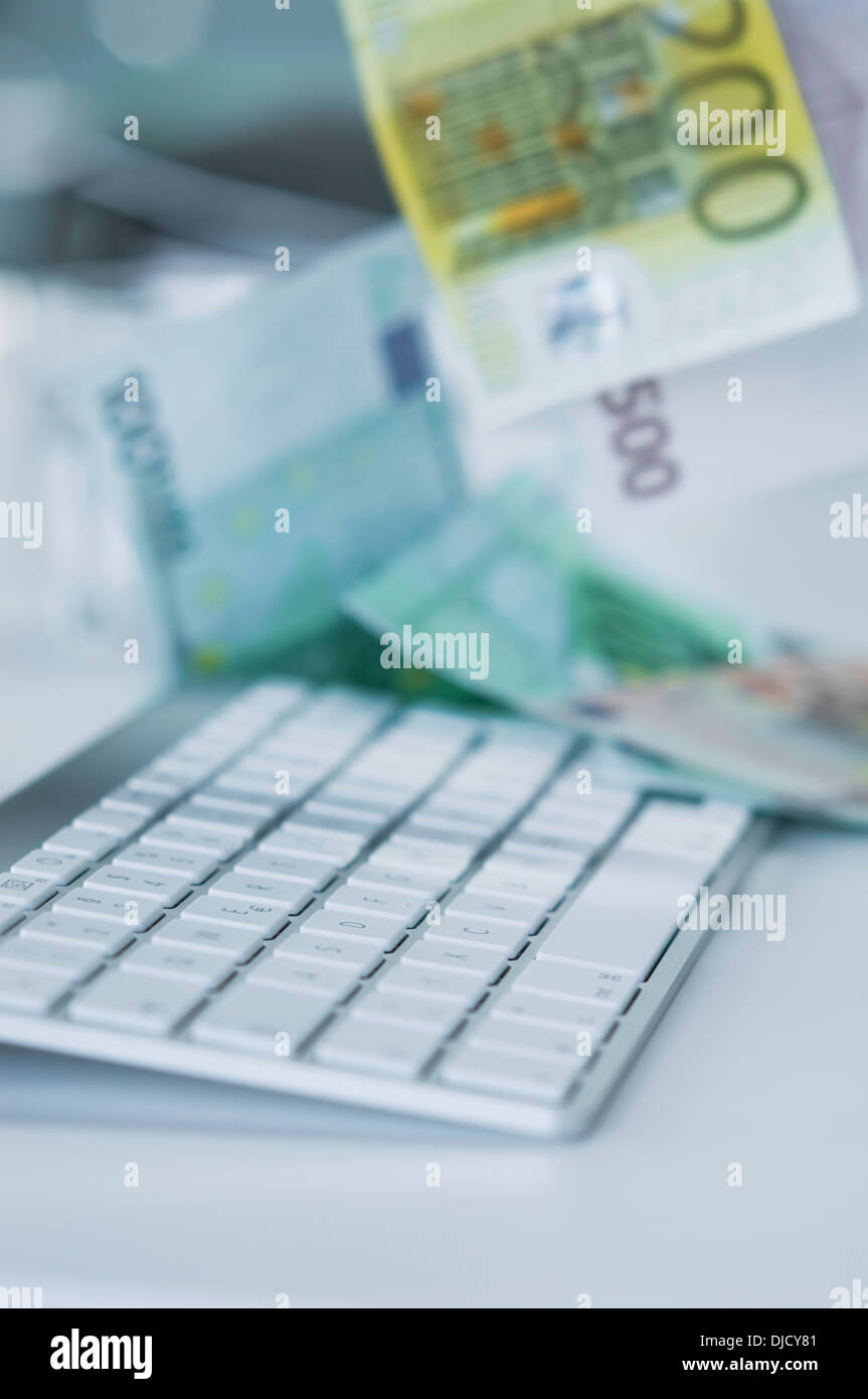 Keyboard and falling euro notes on desk Stock Photo - Alamy