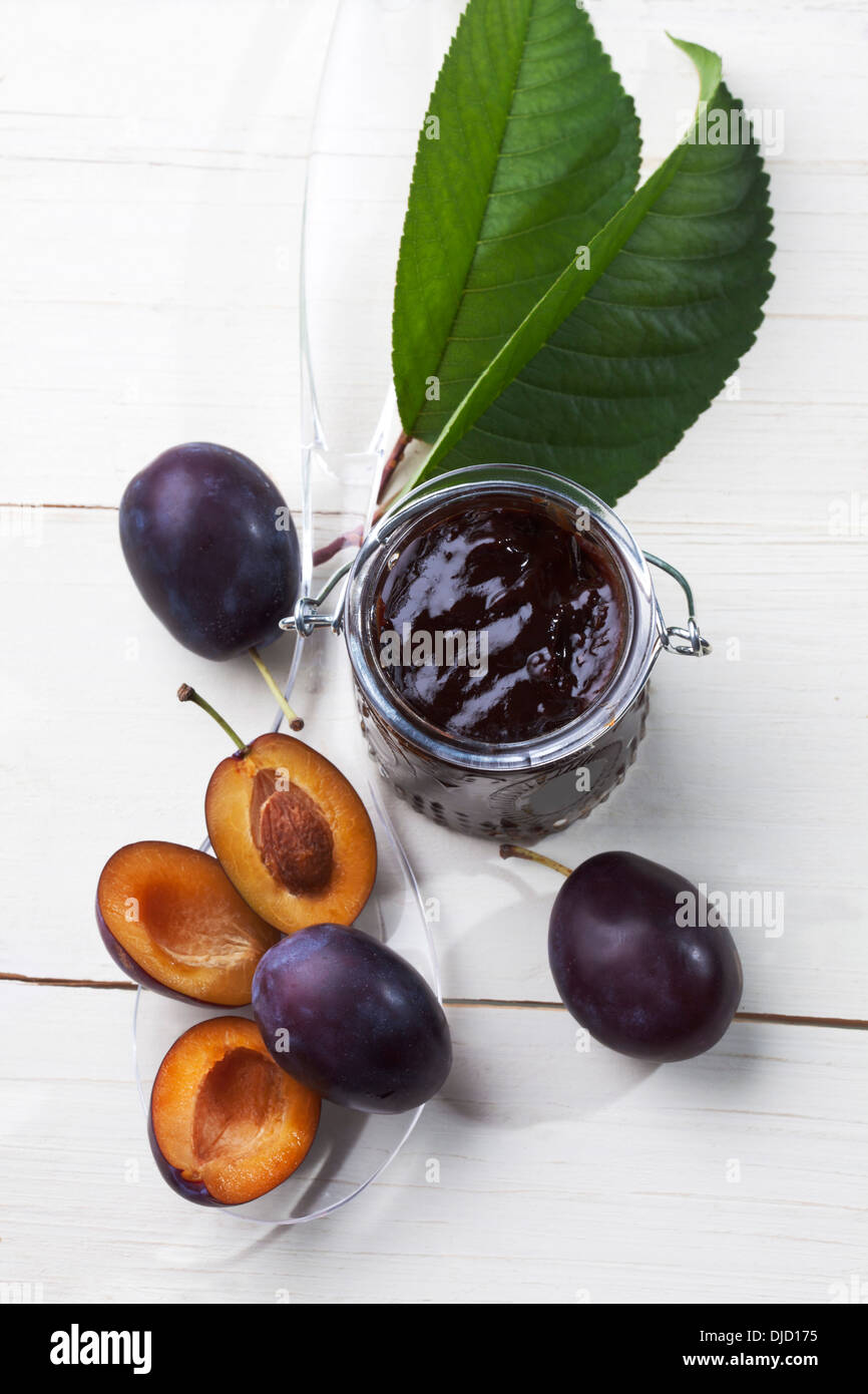 Glass of plum jam and some plums on plastic spoon, studio shot Stock ...