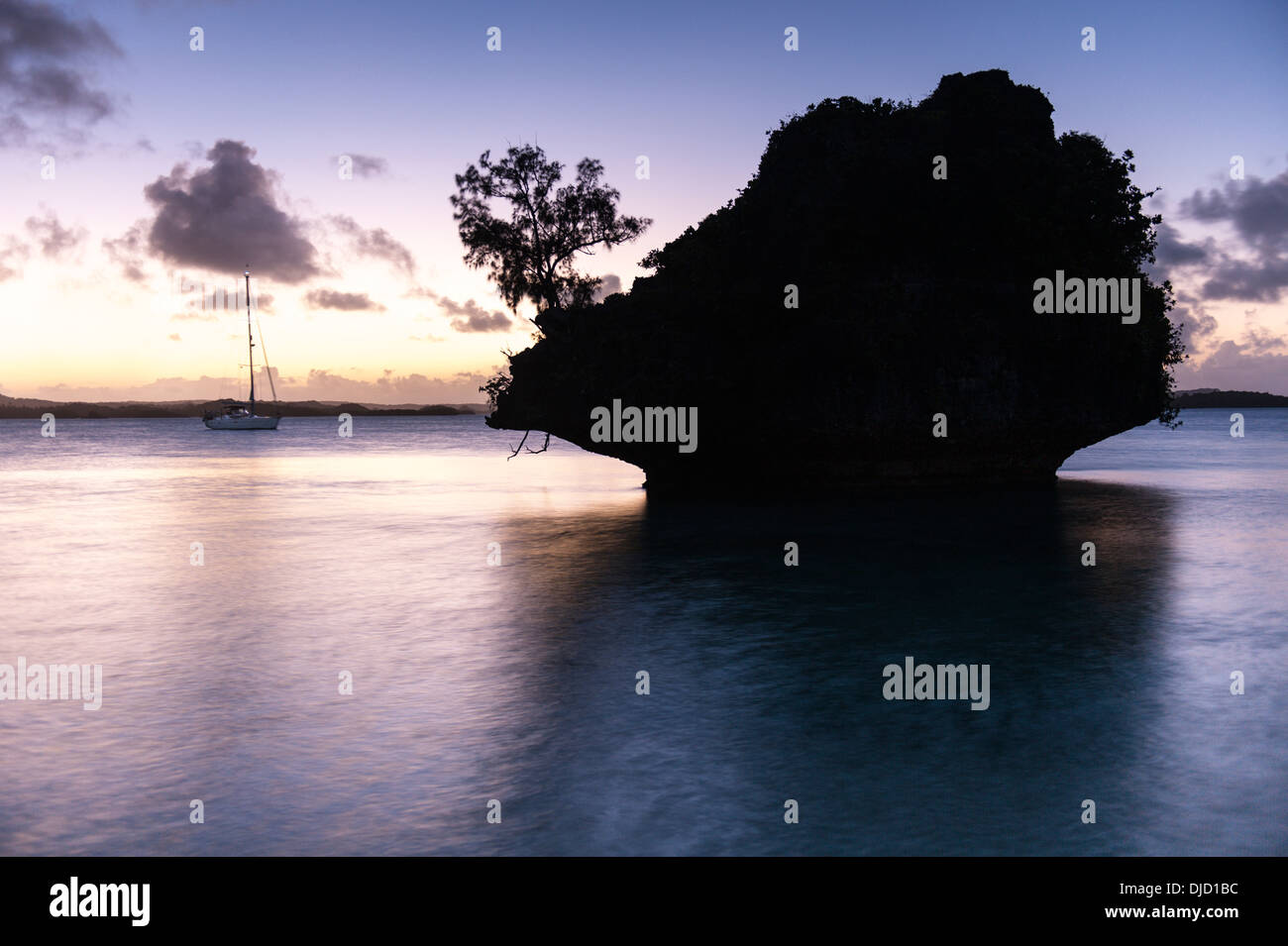 Motu - small limestone islet - at dusk with yacht at anchor, anchorage ...