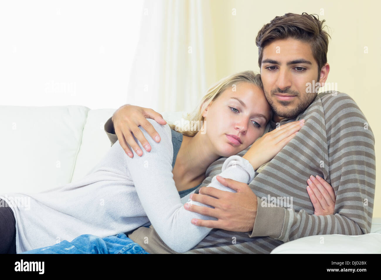 Young couple sitting on couch together Stock Photo - Alamy