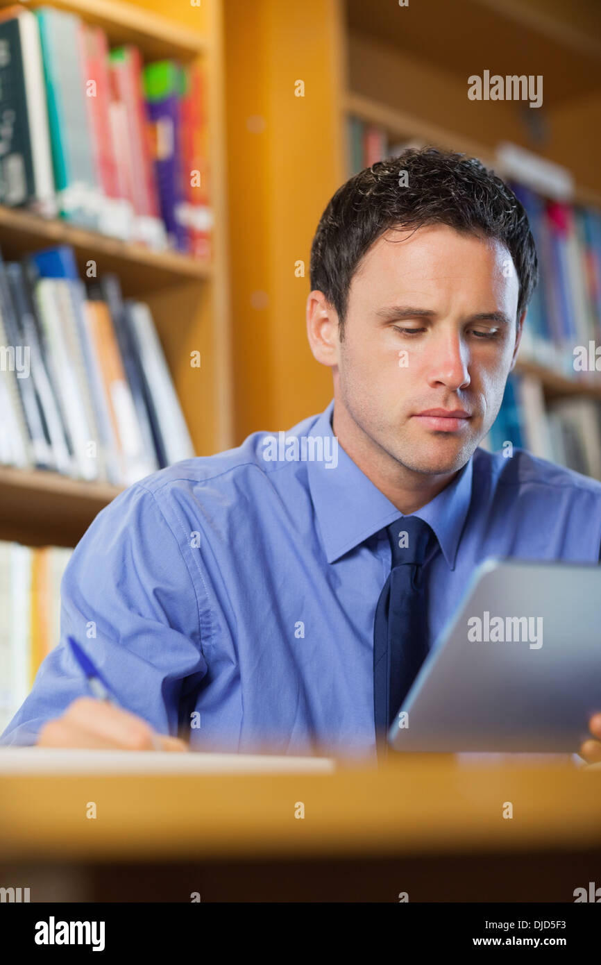 Focused librarian sitting at desk using tablet Stock Photo - Alamy