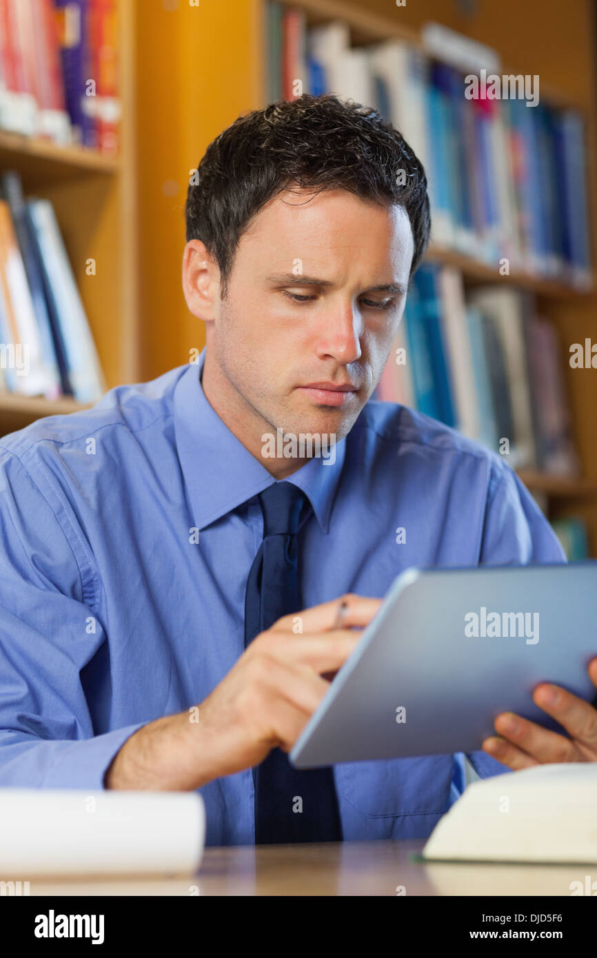 Concentrating librarian sitting at desk using tablet Stock Photo - Alamy