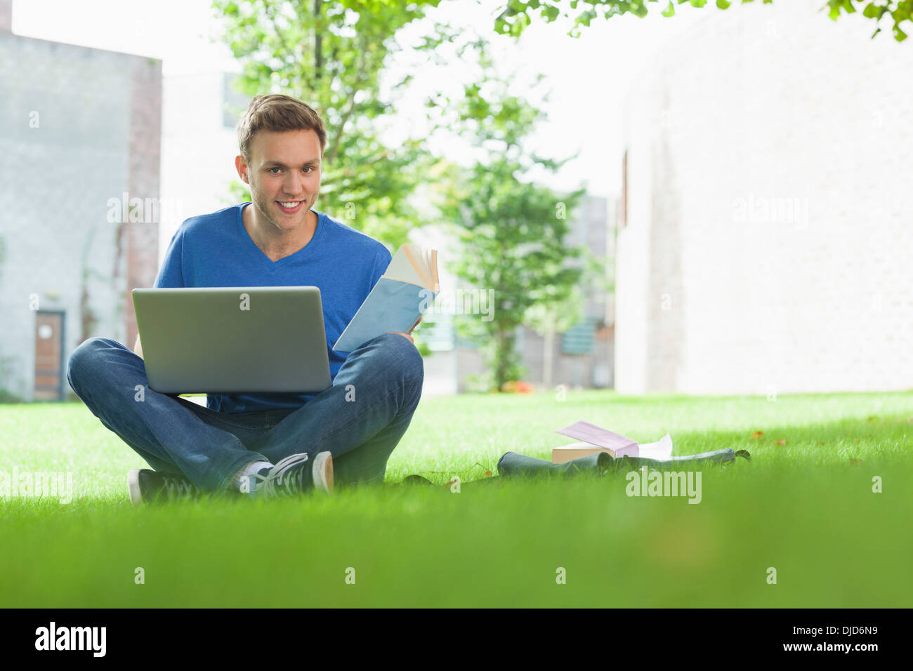 Smiling handsome student sitting under tree studying Stock Photo - Alamy
