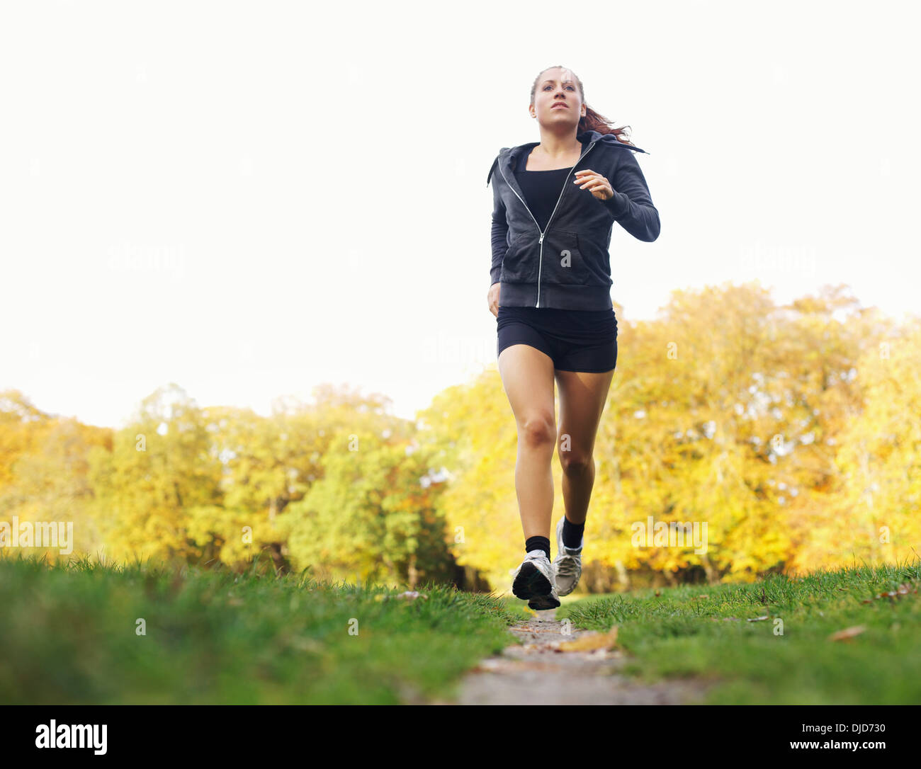 Full length image of healthy young woman jogging in park. Caucasian ...