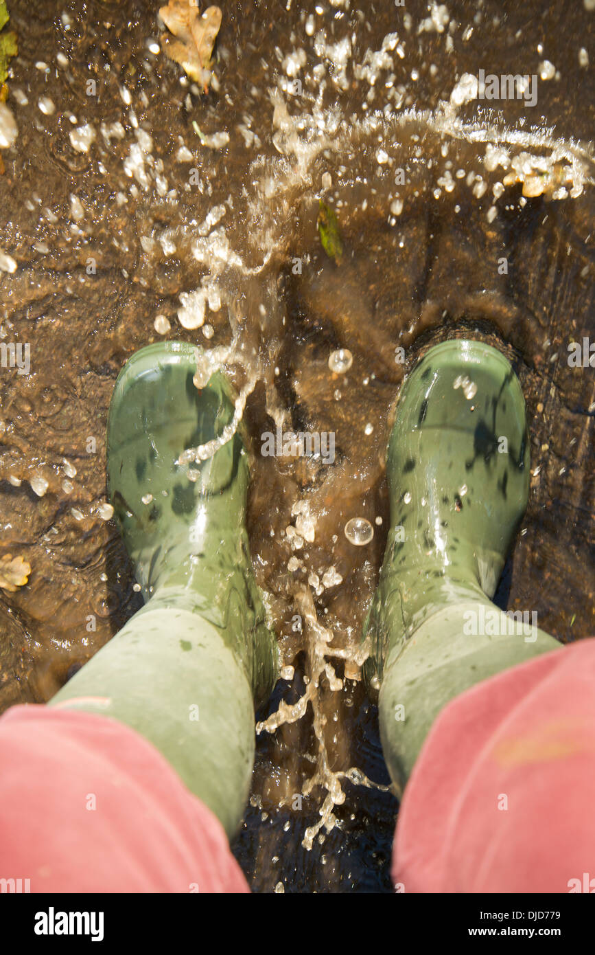 Splashing boots in muddy puddles of water Stock Photo - Alamy