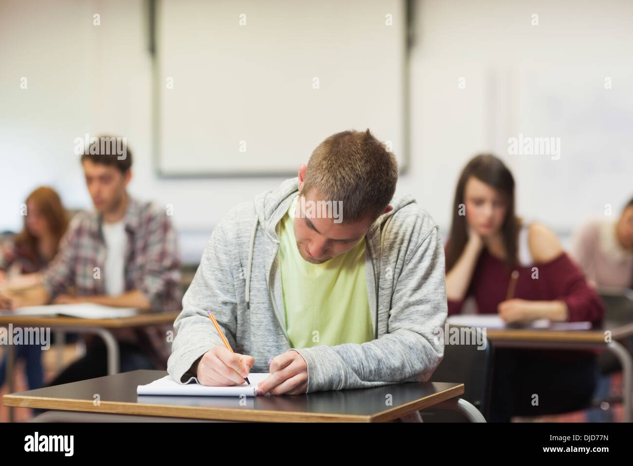 Focused young student taking notes in class Stock Photo - Alamy