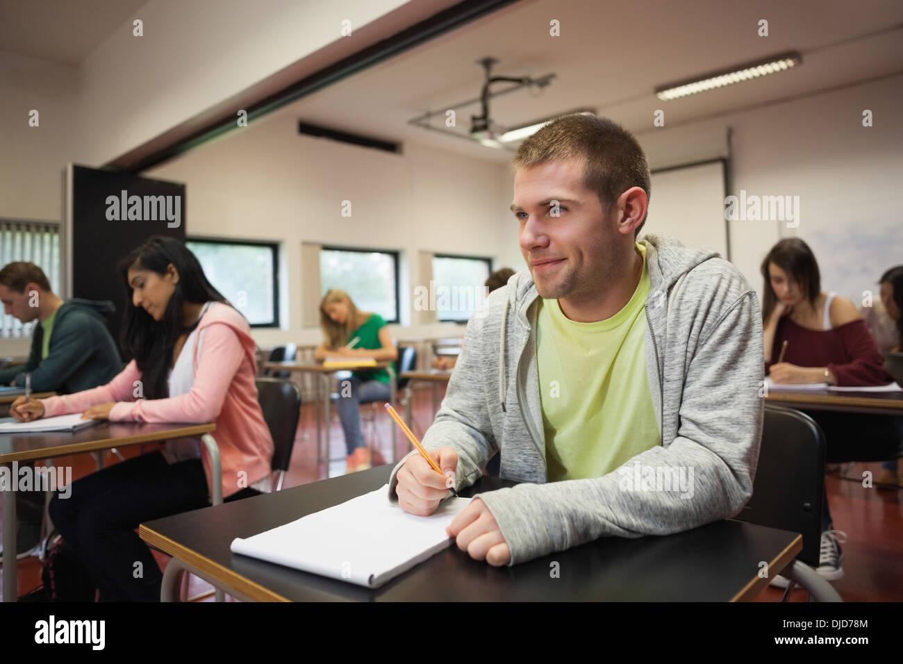 Smiling male student listening in class Stock Photo - Alamy