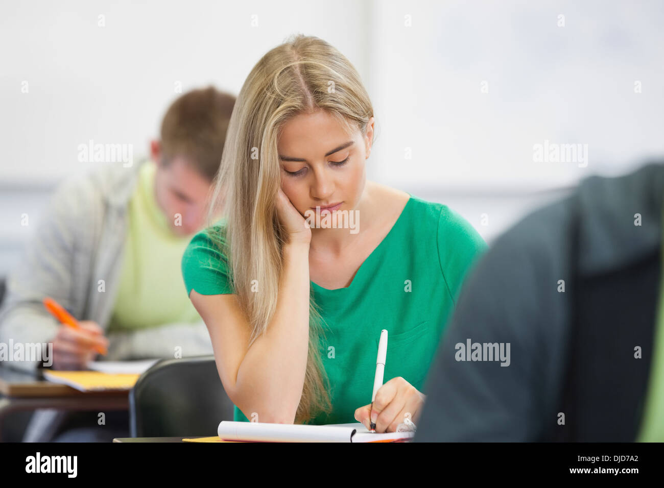 Pretty blonde student taking notes in class Stock Photo - Alamy
