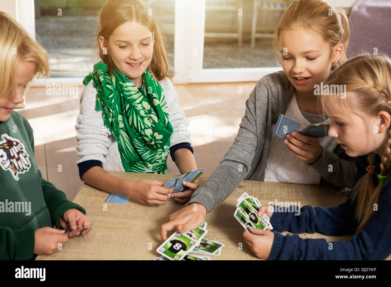 Four children playing card game in living room Stock Photo - Alamy