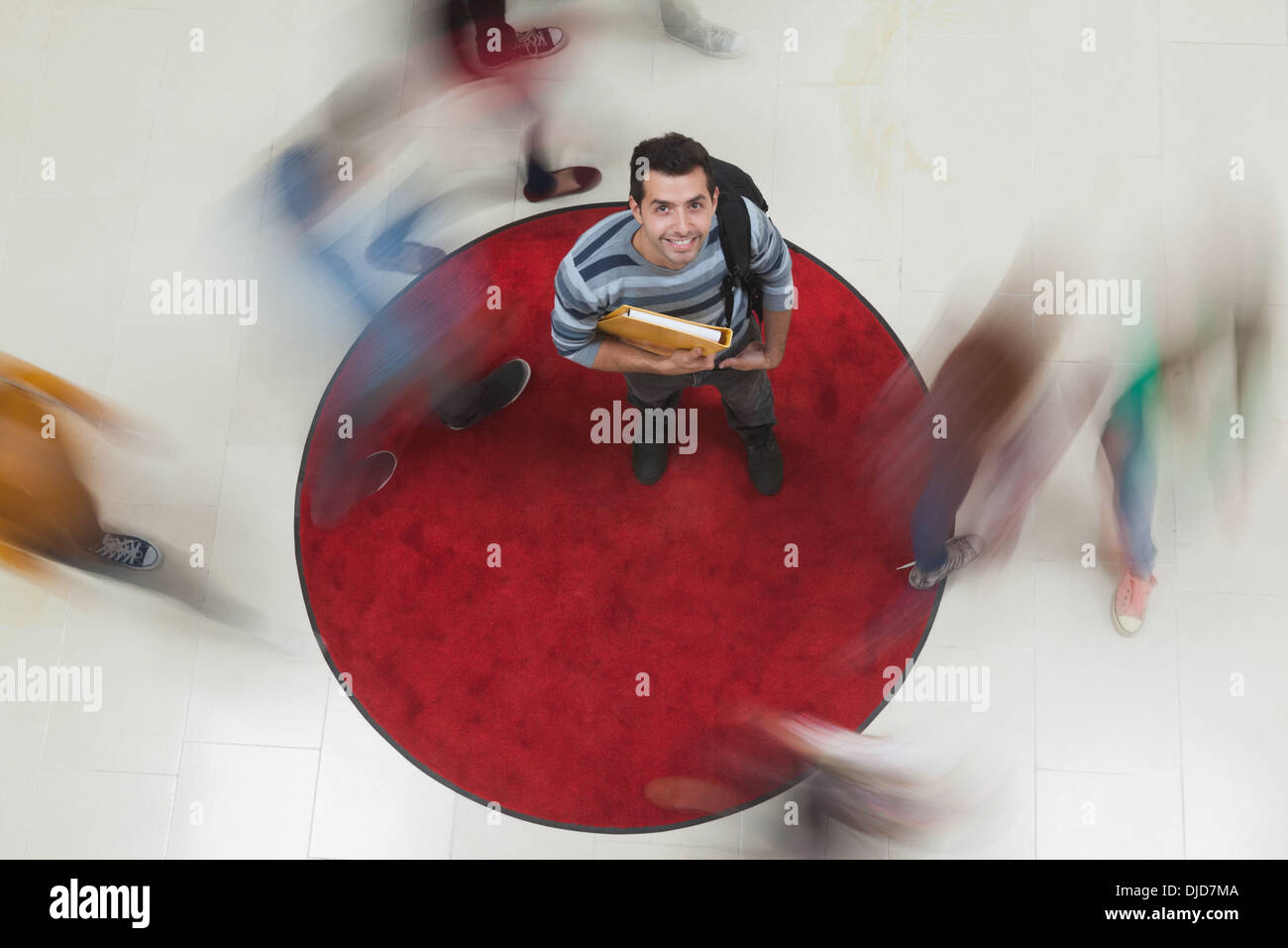 Happy student looking up at camera with others rushing around him Stock ...