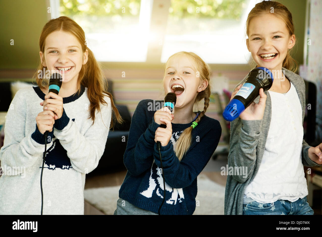 Three girls singing with microphone Stock Photo - Alamy