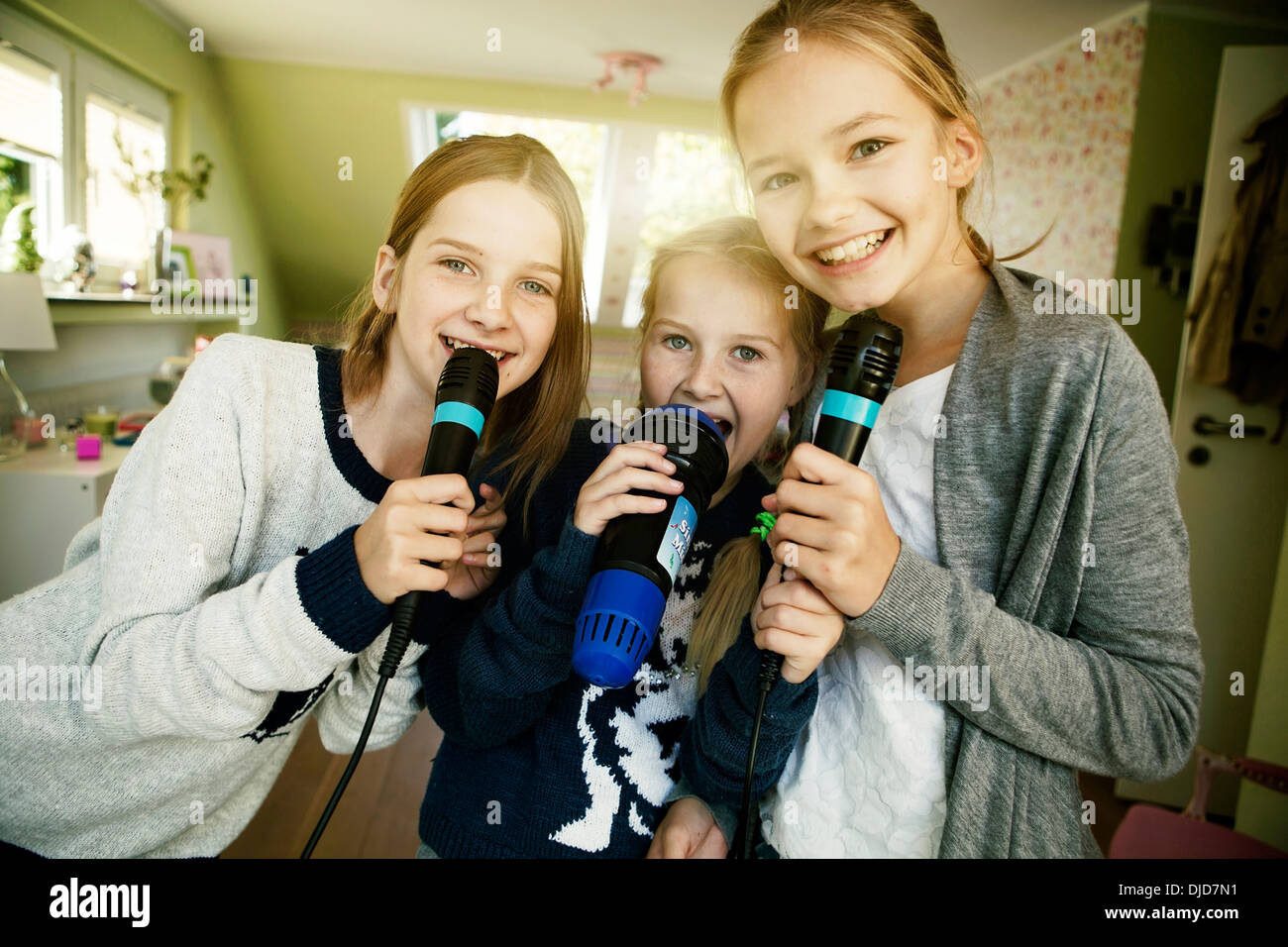 Three girls singing with microphone Stock Photo - Alamy