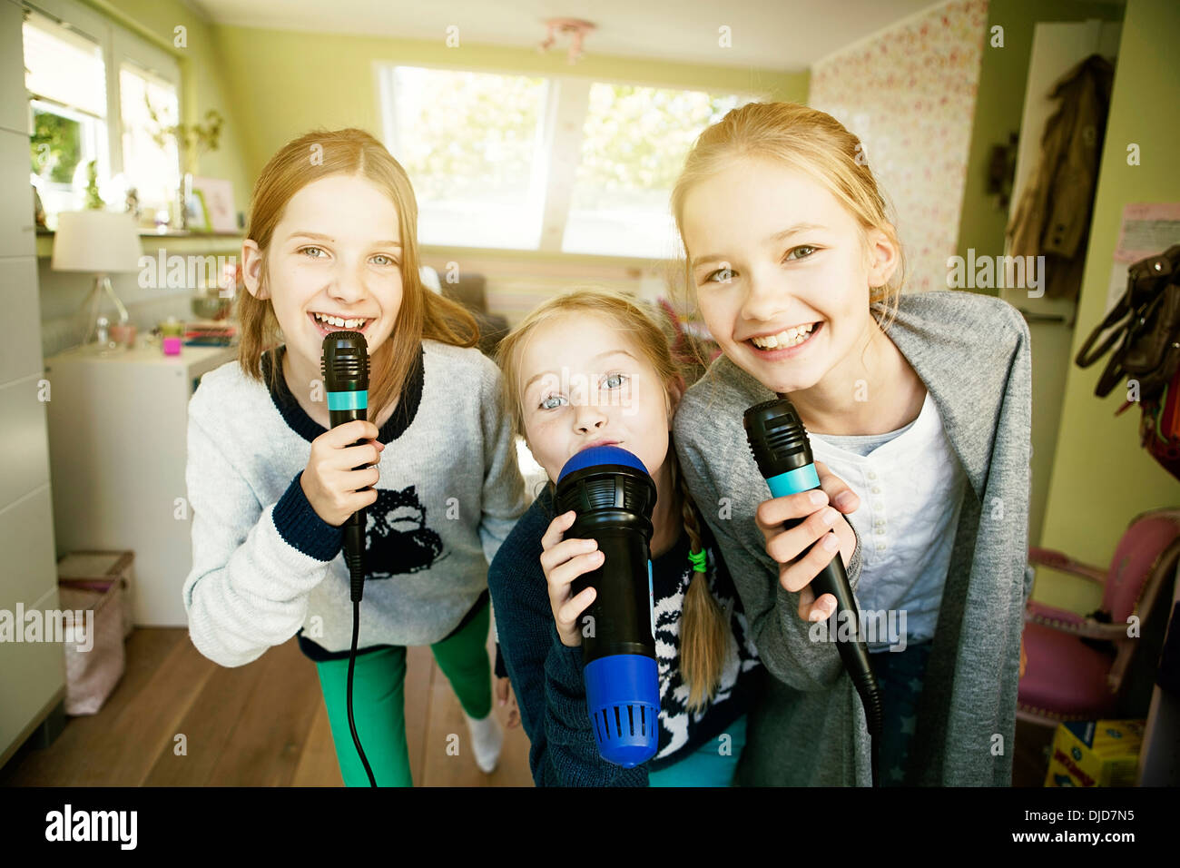 Three girls singing with microphone Stock Photo - Alamy