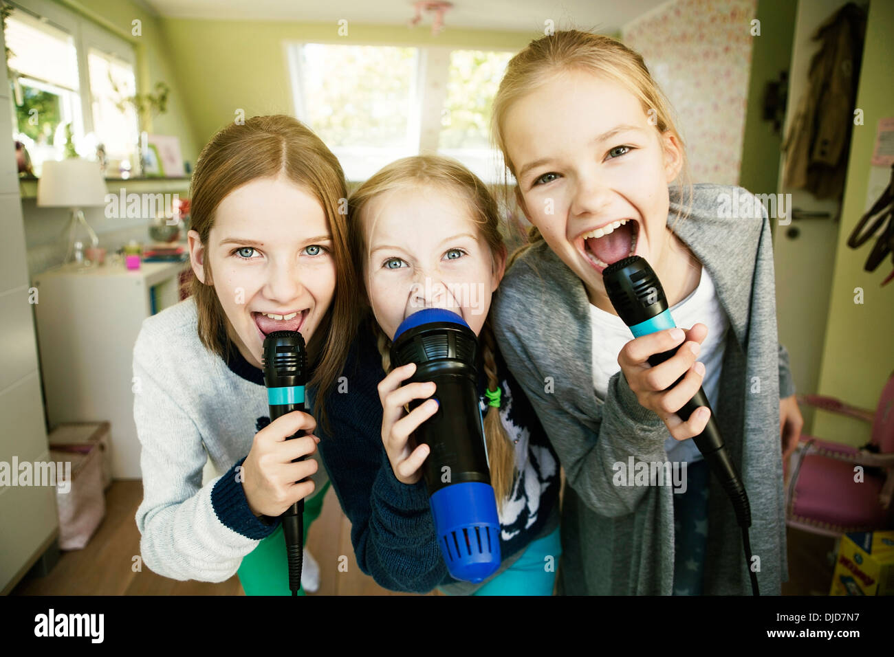 Three girls singing with microphone Stock Photo - Alamy