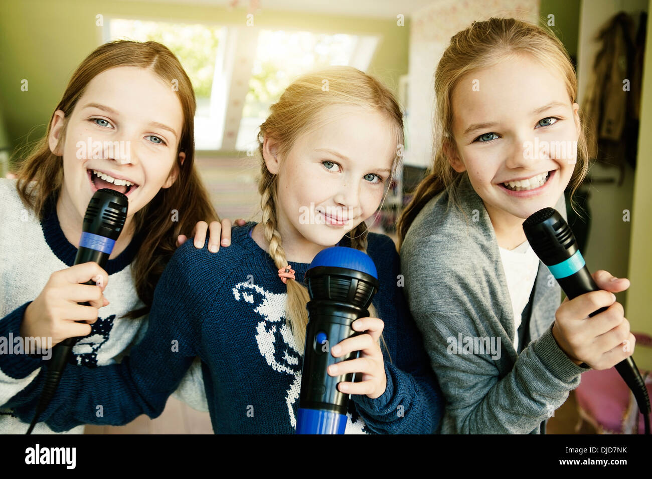 Three girls singing with microphone Stock Photo - Alamy
