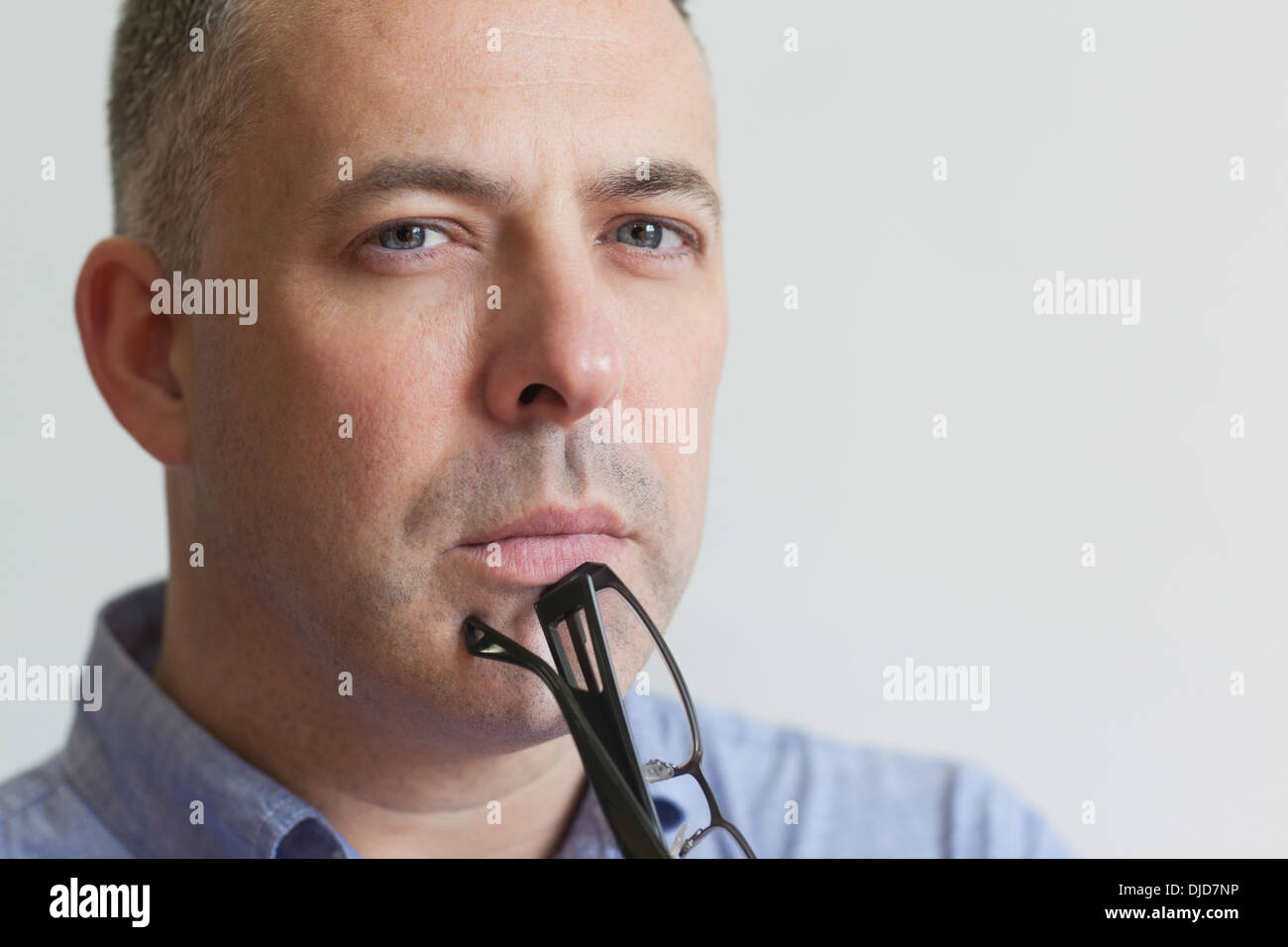 Thinking lecturer looking at camera holding his glasses Stock Photo - Alamy