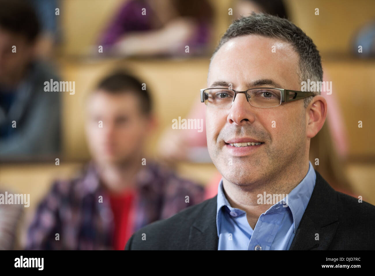 Happy lecturer looking at camera in lecture hall Stock Photo - Alamy