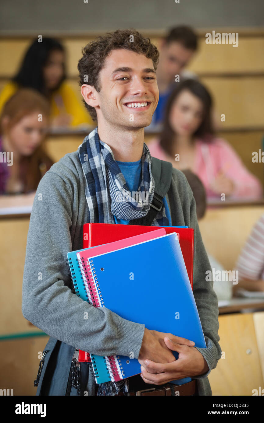 Happy handsome student standing in front of his class in lecture hall ...