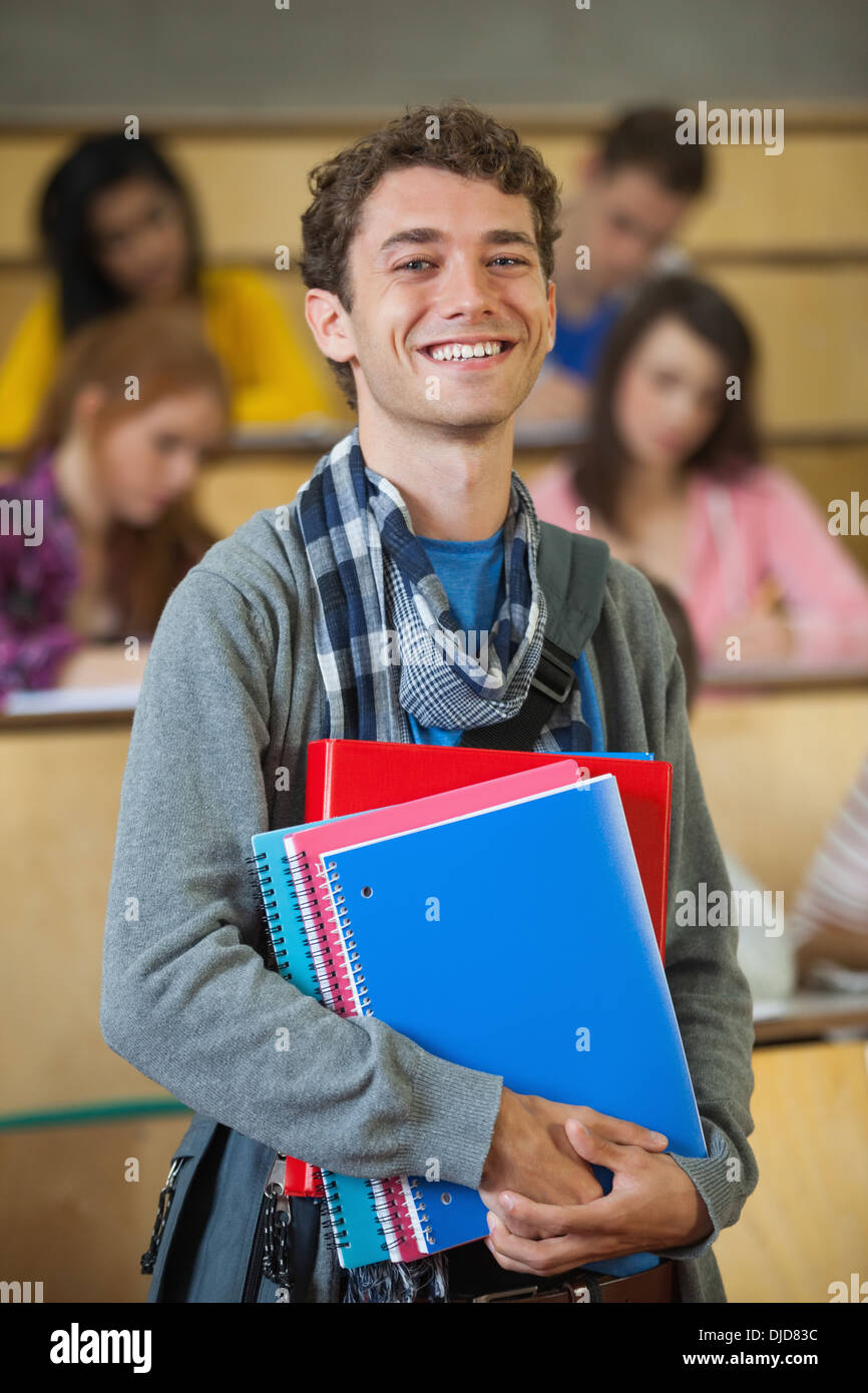 Smiling handsome student standing in front of his class in lecture hall ...