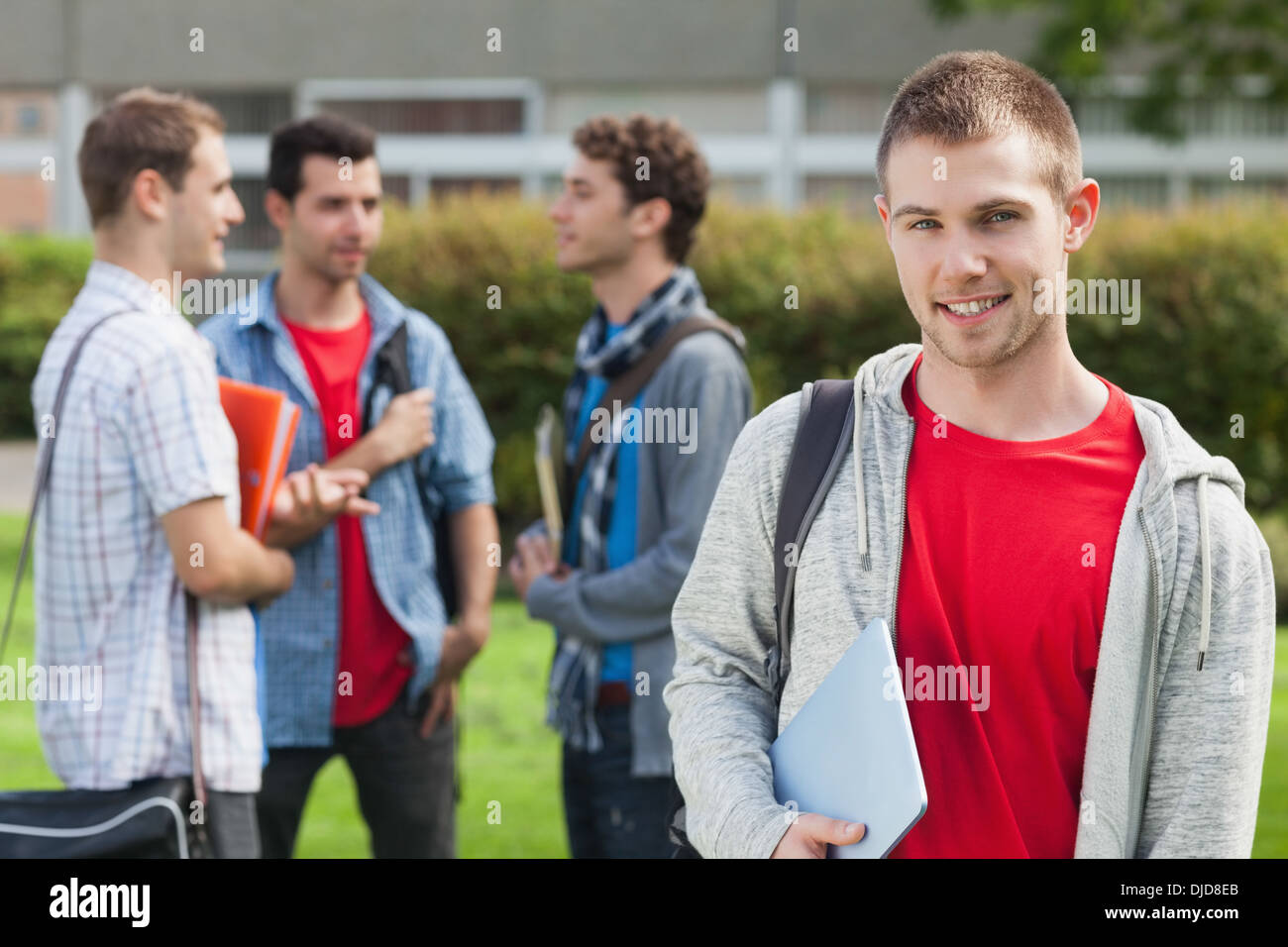 Cheerful male student smiling at camera in front of his classmates ...