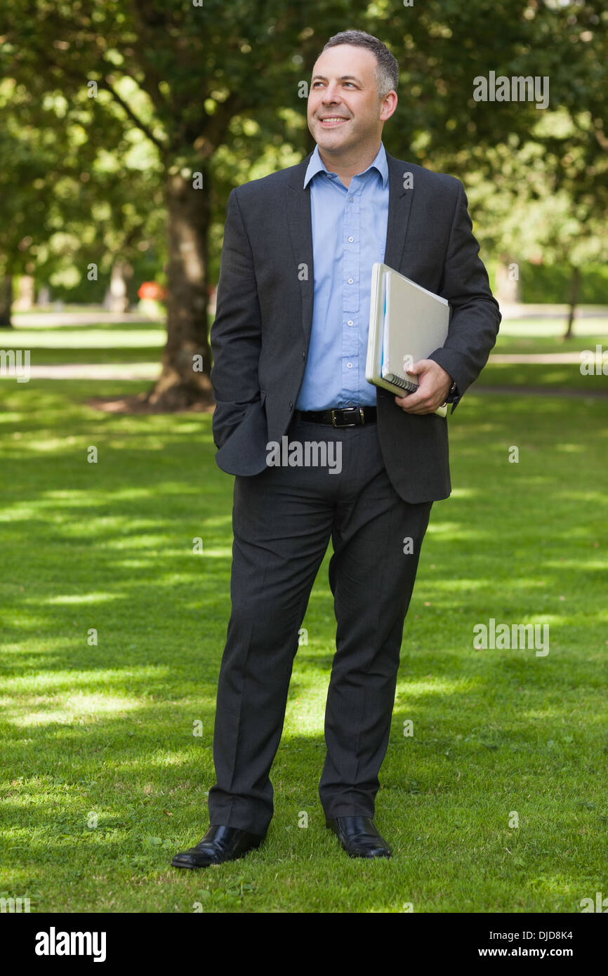 Thoughtful professor standing on campus holding notepads Stock Photo ...