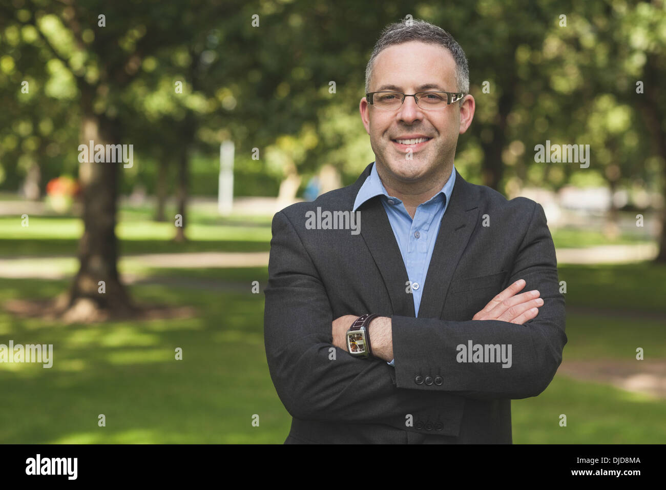 Happy professor looking at camera with arms folded on campus Stock ...