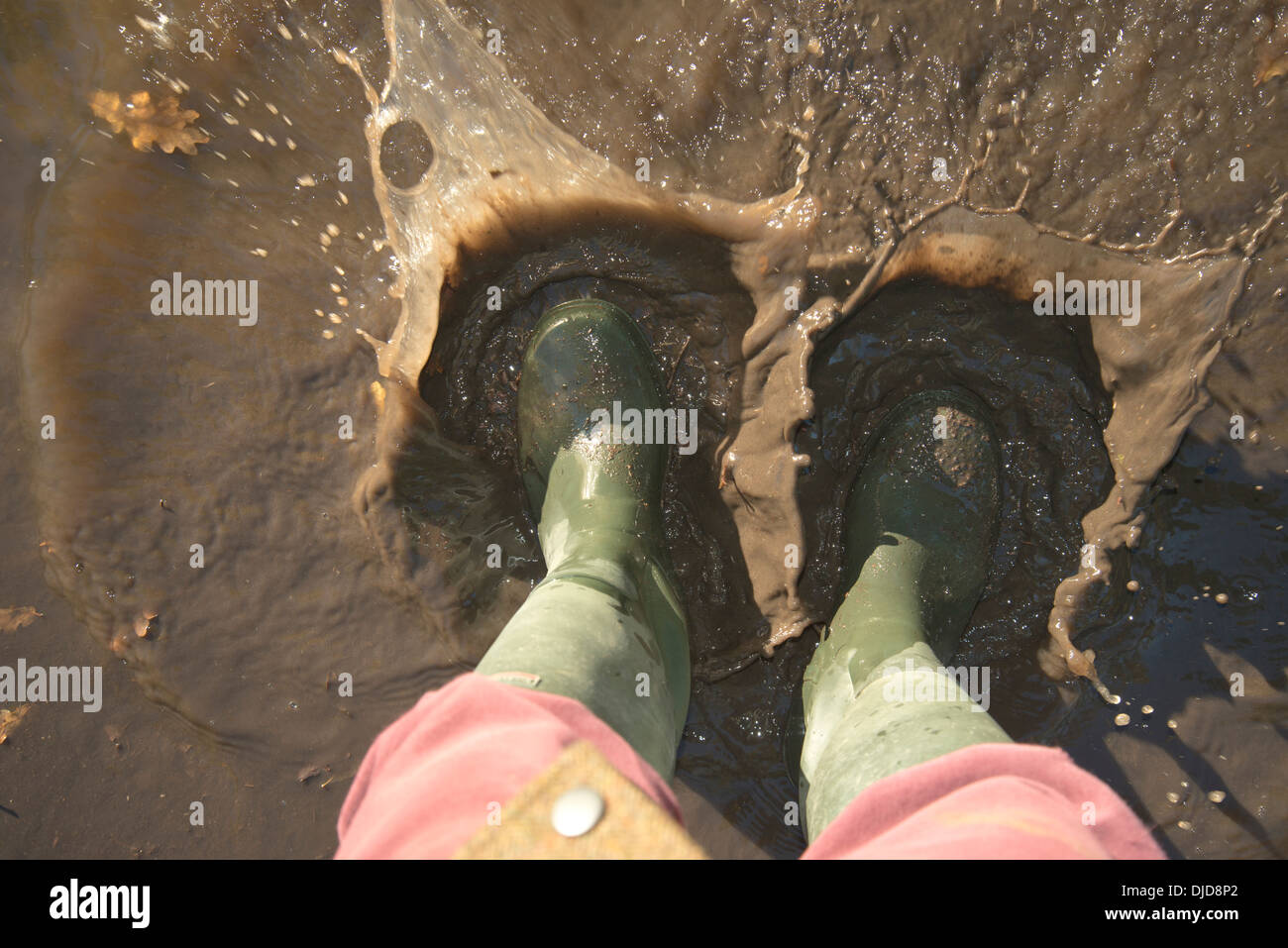 Splashing boots in muddy puddles of water Stock Photo - Alamy