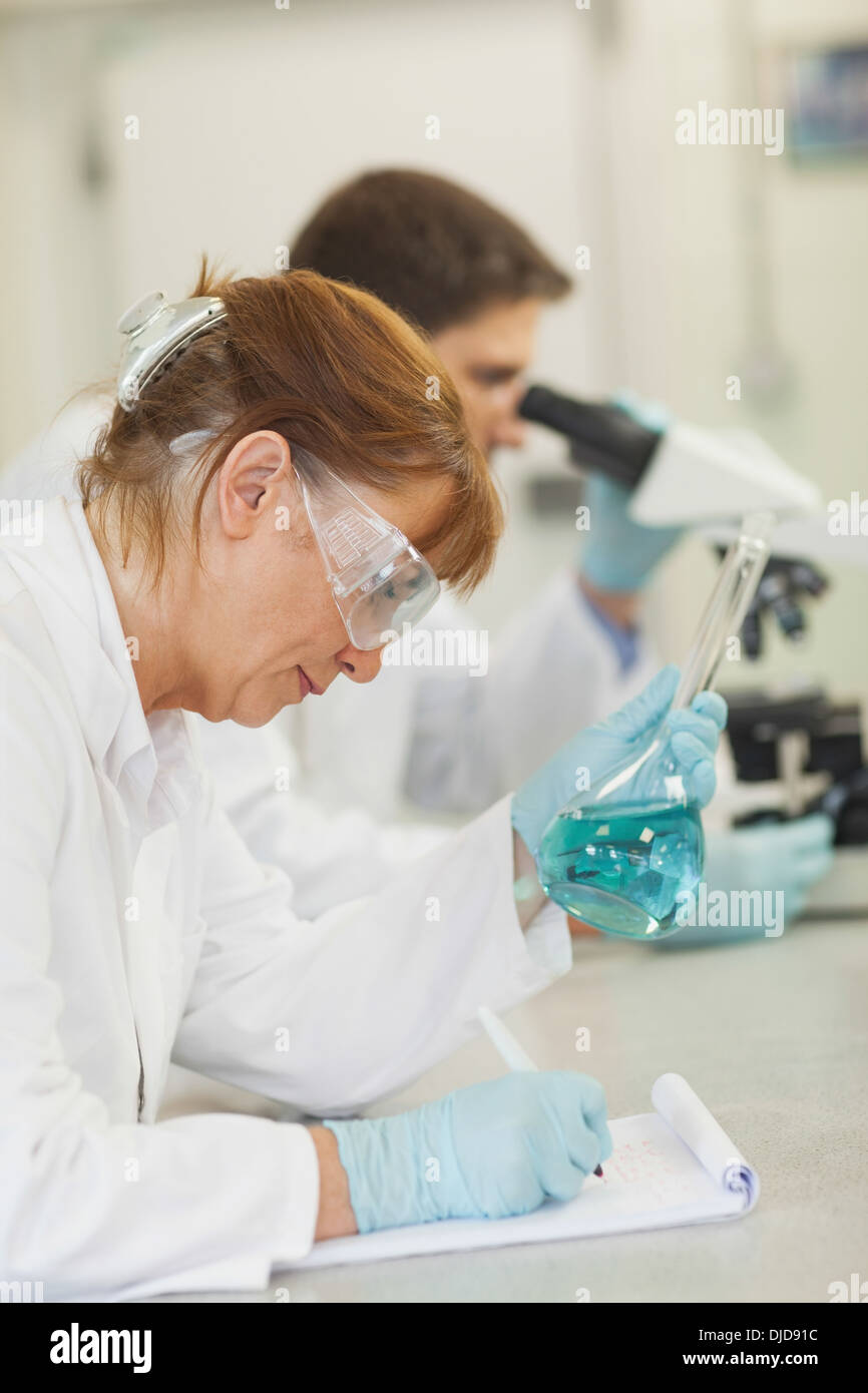 Attractive female scientist writing on a clipboard Stock Photo - Alamy