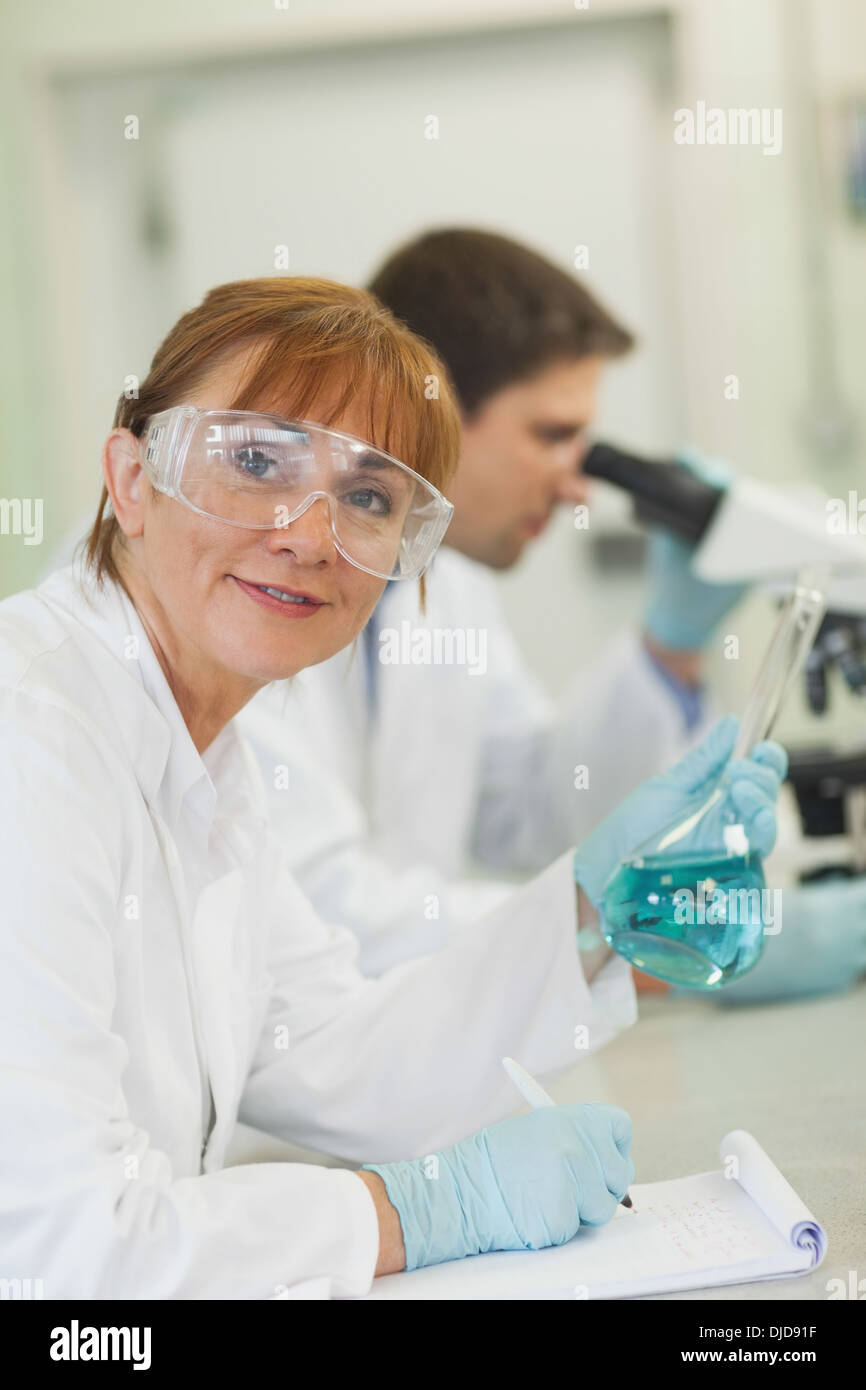 Cheerful female scientist standing in a laboratory while writing Stock ...