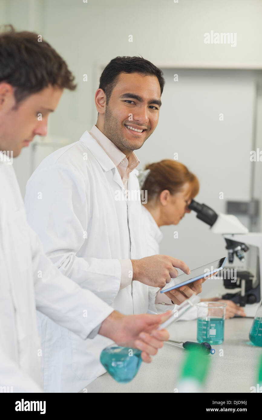 Handsome male scientist holding his white tablet standing in the ...