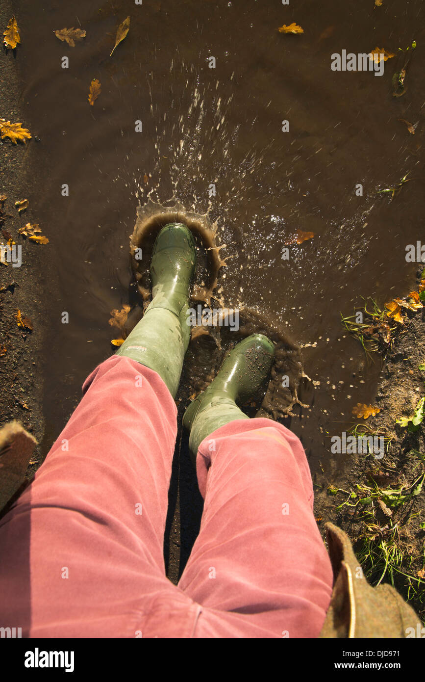 Splashing boots in muddy puddles of water Stock Photo - Alamy