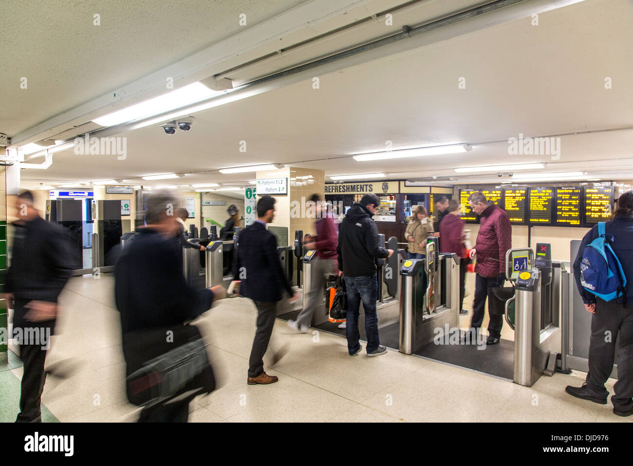 Commuters passing through ticket barrier at railway station, England ...