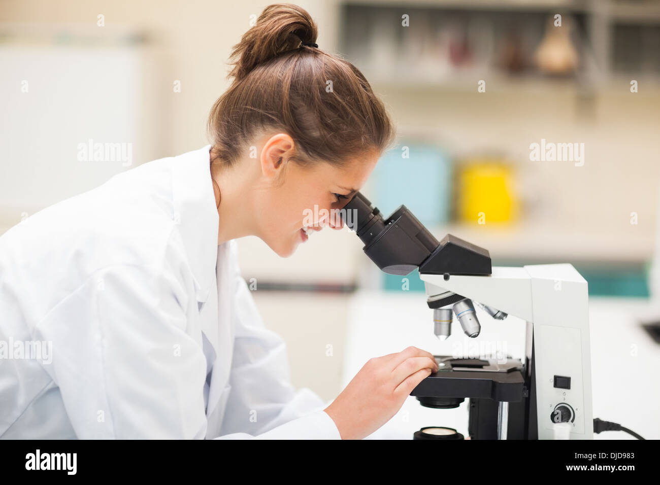 Smiling brunette student looking through microscope Stock Photo - Alamy