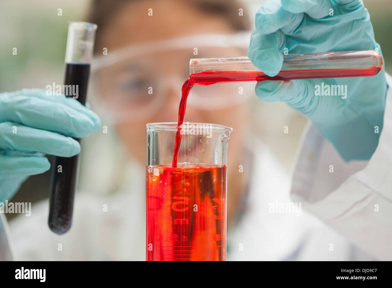 Student pouring red liquid beaker Stock Photo - Alamy