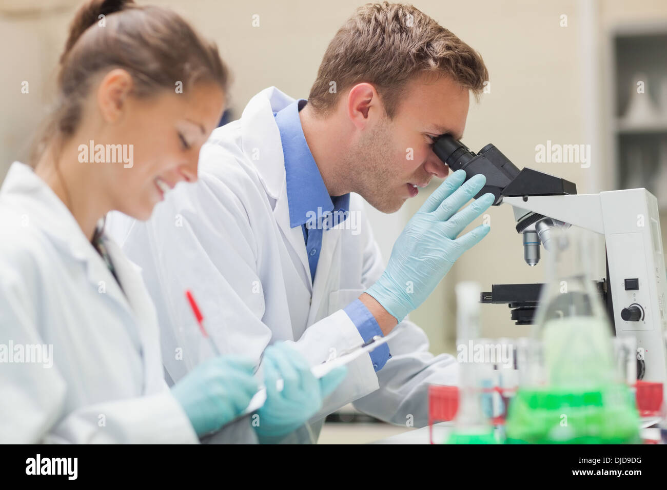 Two happy students looking through microscope and taking notes Stock ...