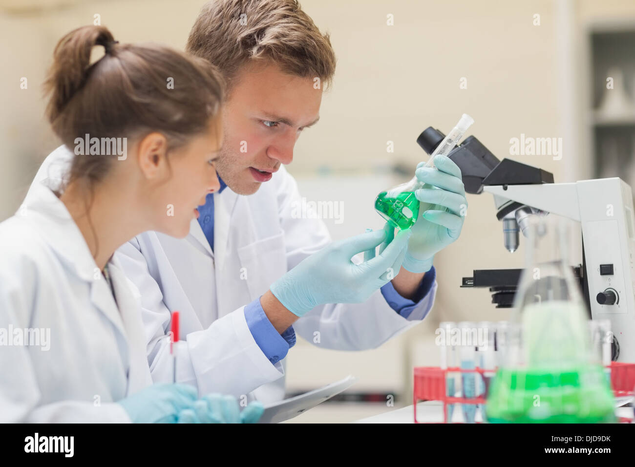 Two focused students looking through microscope and taking notes Stock ...