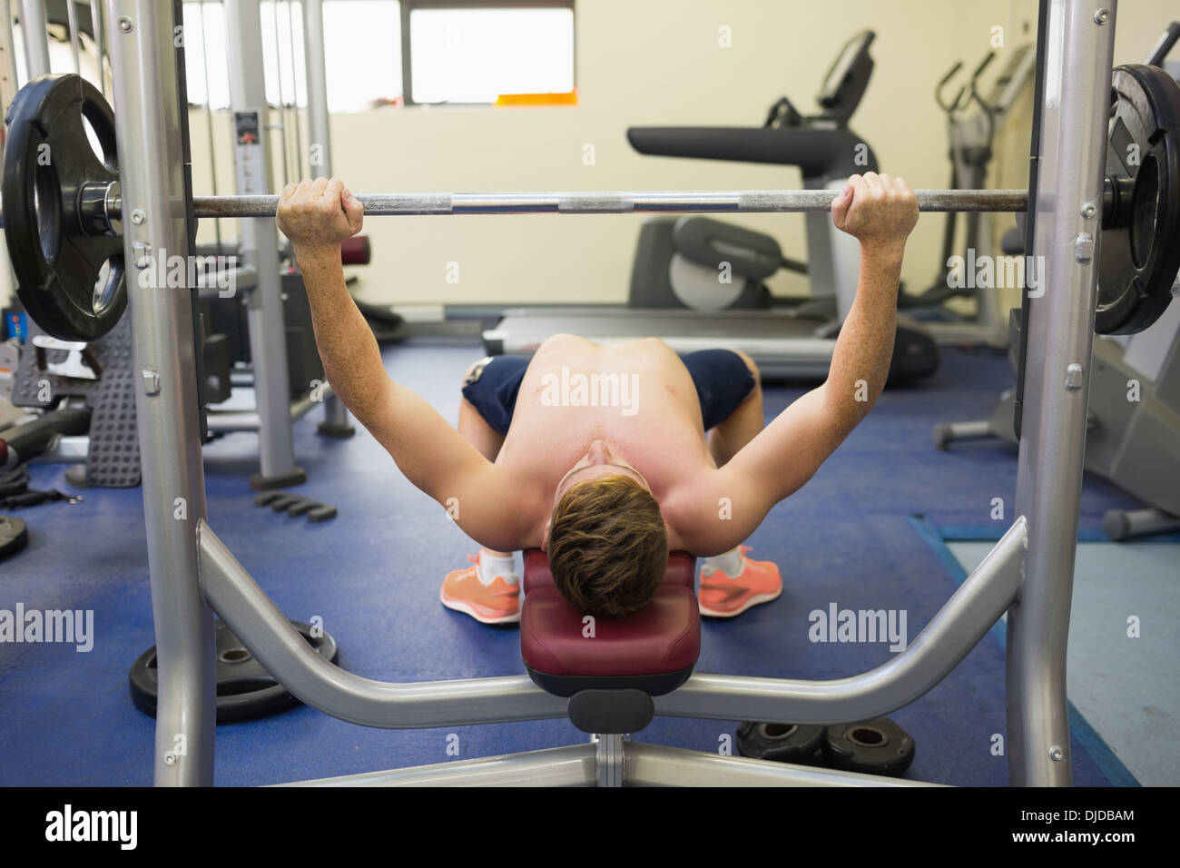 Muscular handsome man lifting barbell lying on bench Stock Photo - Alamy